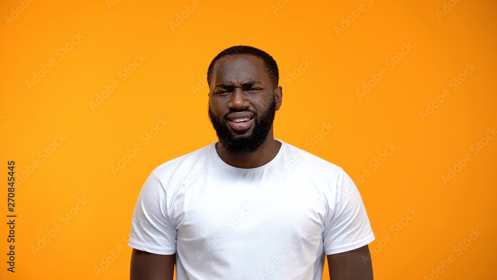 Displeased African-American man looking at camera isolated on yellow ...