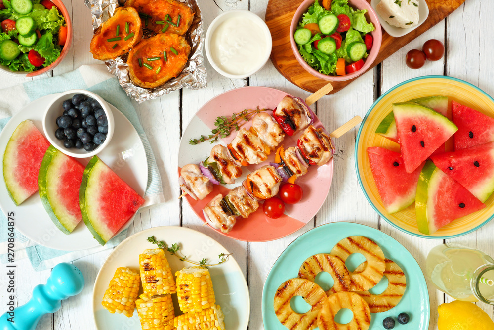 Summer BBQ or picnic food concept. Selection of fruits, salad, grilled ...