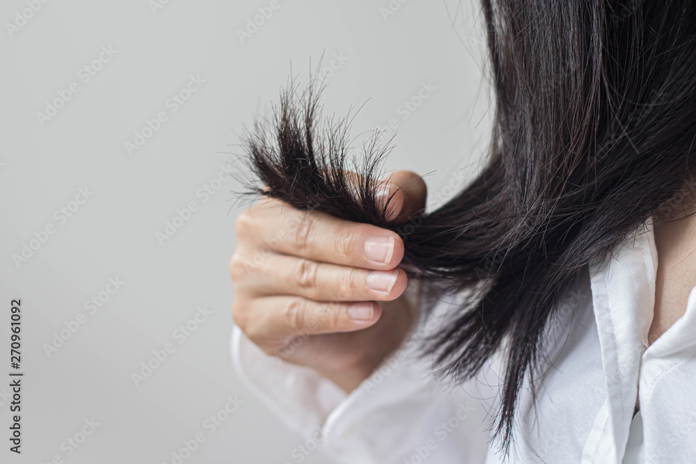 Closeup of woman's hand holdind her long hair and looking at damaged ...