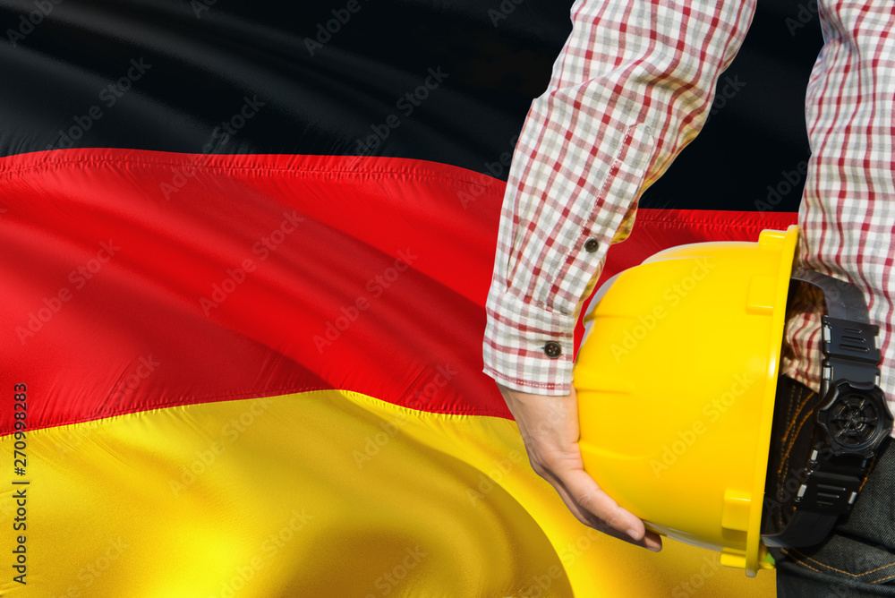German Engineer is holding yellow safety helmet with waving Germany ...