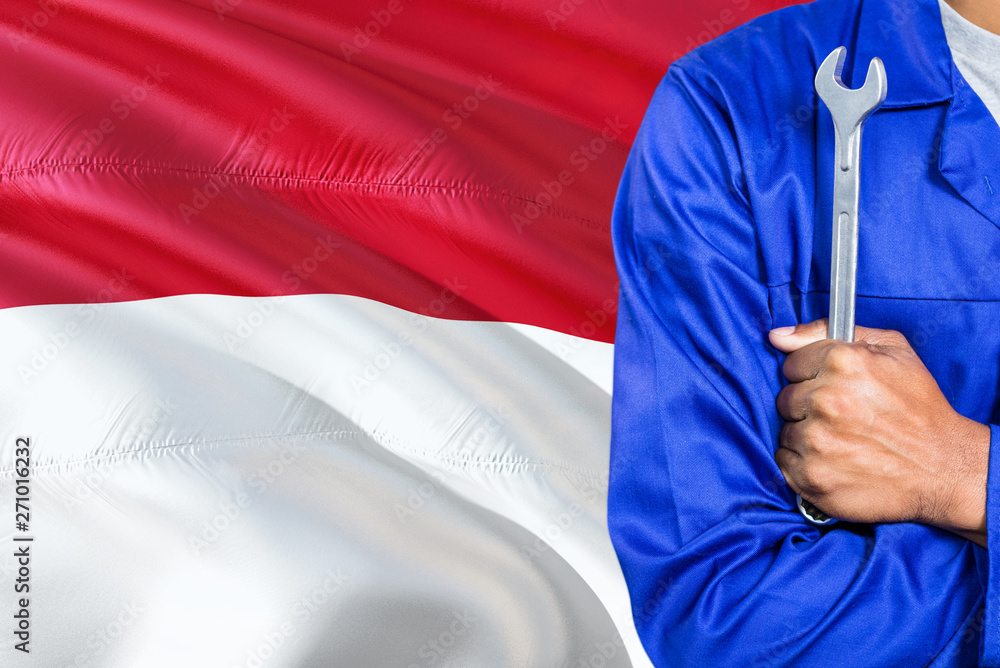 Indonesian Mechanic in blue uniform is holding wrench against waving ...