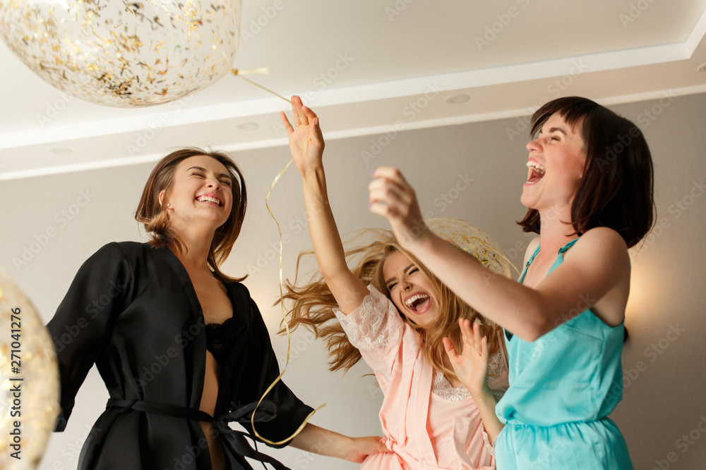 Women party. Three attractive young women having fun while jumping on ...