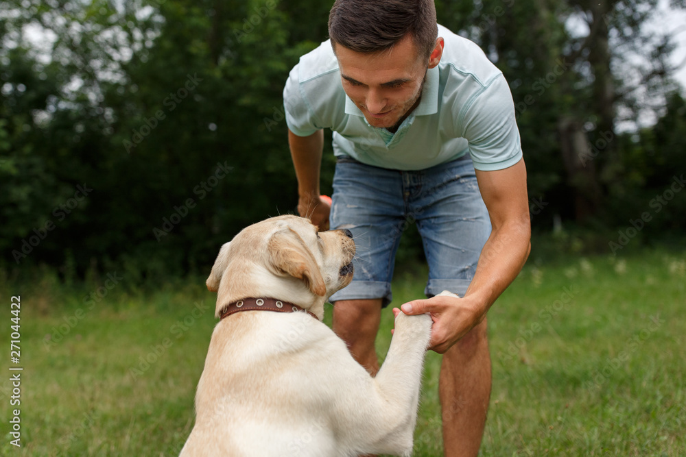 Friendship of man and dog. Happy young man holding a paw of a dog ...