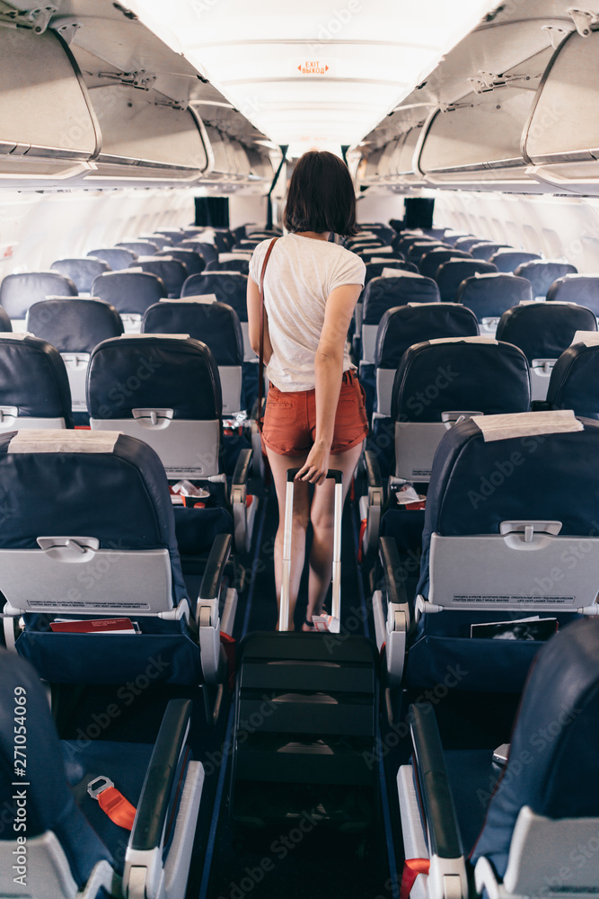 Back view of young woman walking the aisle on plane Stock Photo | Adobe ...