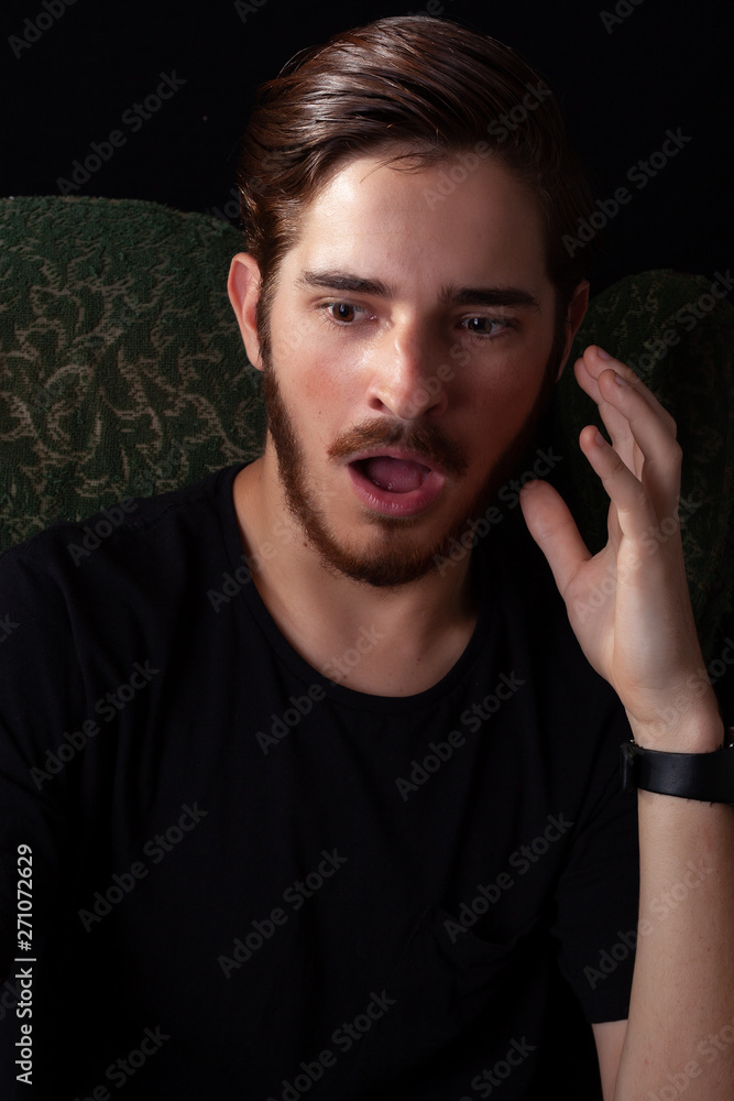 Extreme close up of young adult male looking left, hand to cheek mouth ...