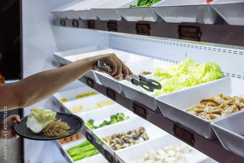 Hand select and pinching fresh vegetables in black plate from food line ...