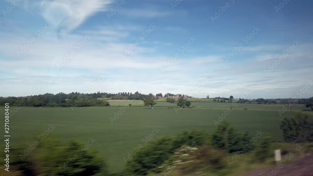 English countryside from a train window. Fields, trees and cloudy sky ...