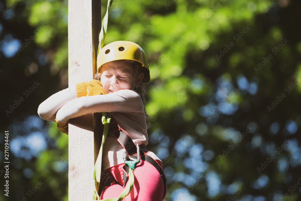 Rope park. Happy Little girl climbing a tree. Cargo net climbing and ...