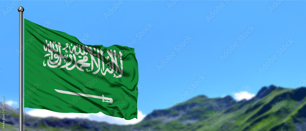 Saudi Arabia flag waving in the blue sky with green fields at mountain ...