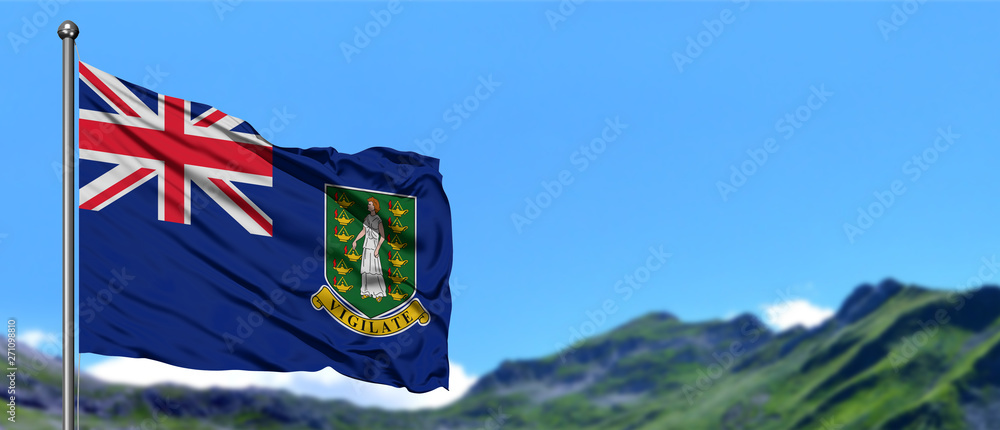 British Virgin Islands flag waving in the blue sky with green fields at ...
