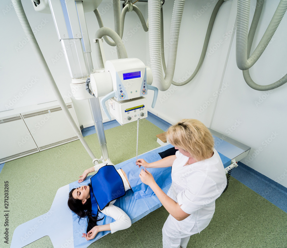 Radiologist and patient in a x-ray room. Classic ceiling-mounted x-ray ...