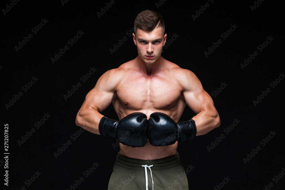 Muscular young man in black boxing gloves and shorts shows the ...