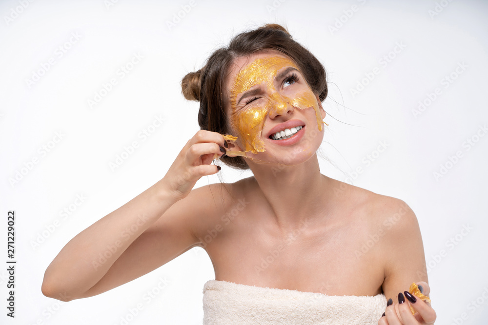 A young girl, 25 years old, removes a cosmetic mask from her face ...