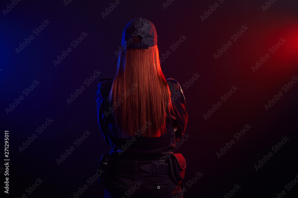 Serious female police officer is posing for the camera against a black ...