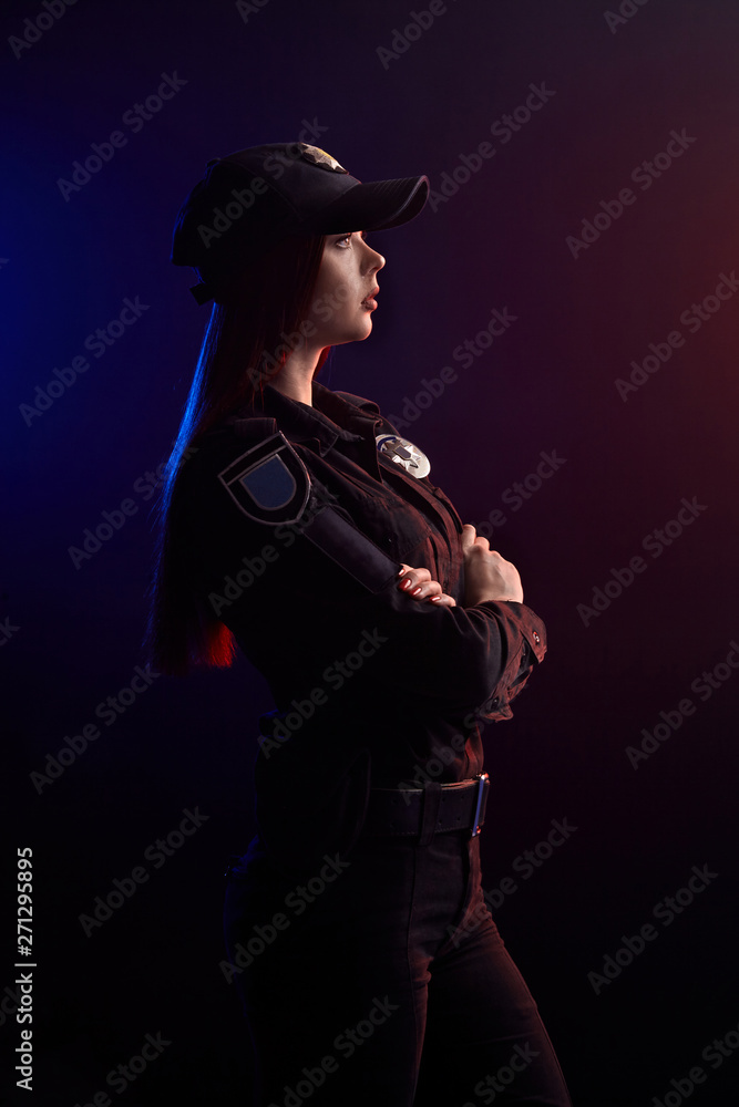 Serious female police officer is posing for the camera against a black ...