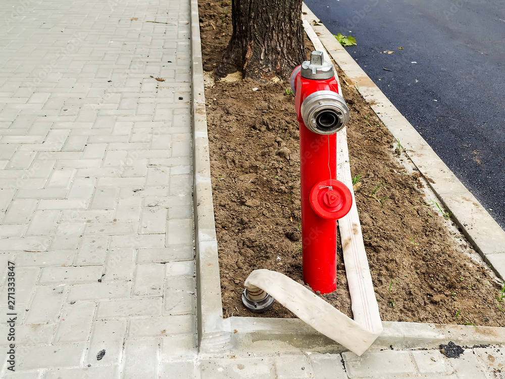 Red fire hydrant with an opened seal and a long white fire hose without ...