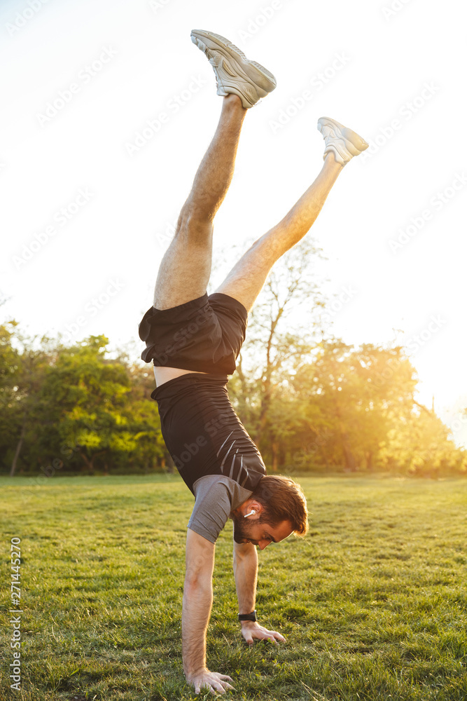 Handsome young strong sports man posing outdoors at the nature park ...