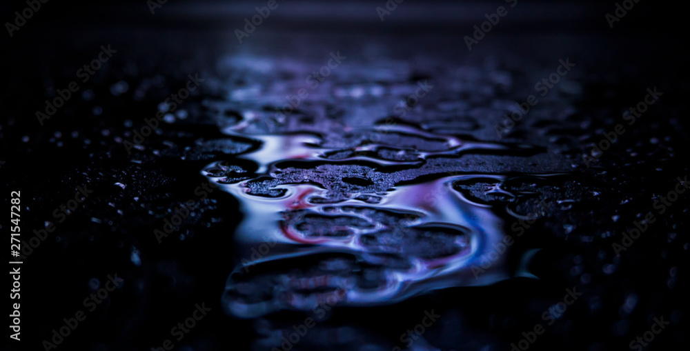 Dark background. Spilled liquid on the mirror surface, the reflection ...