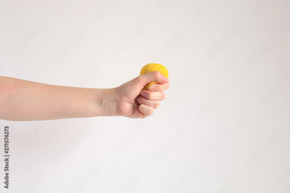 Hand pressing yellow squishy ball for exercise hand muscle and fingers ...