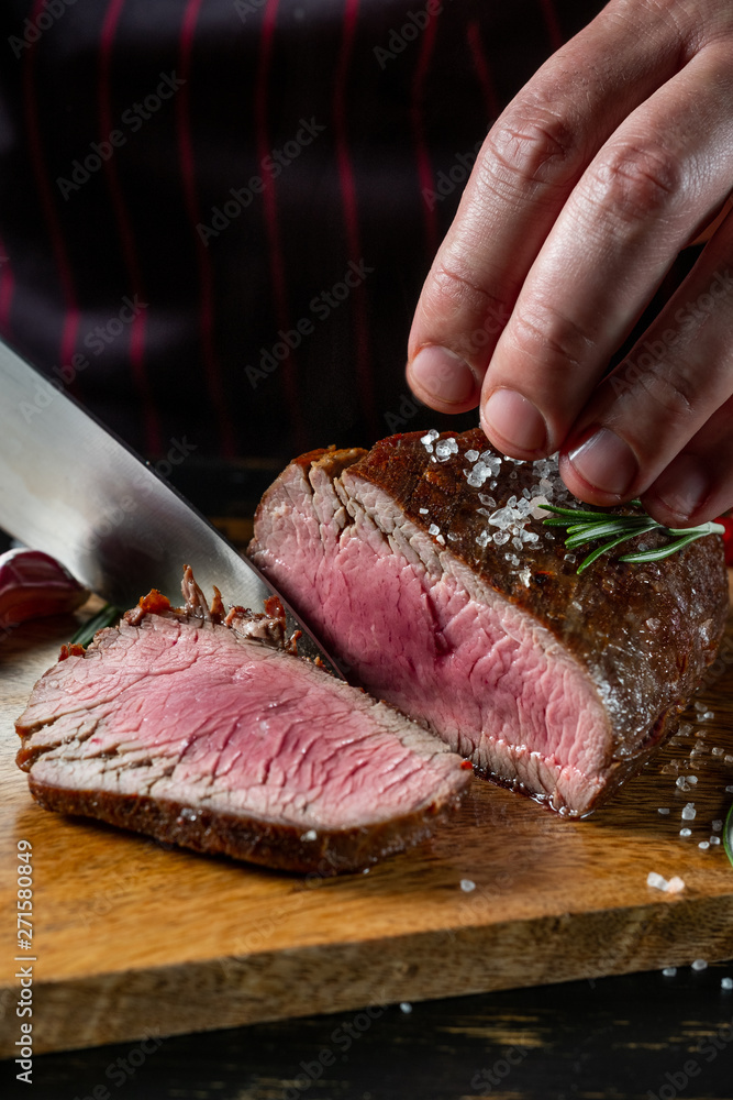 Slicing juicy beef steak by knife in chef hands closeup. Food cooking ...