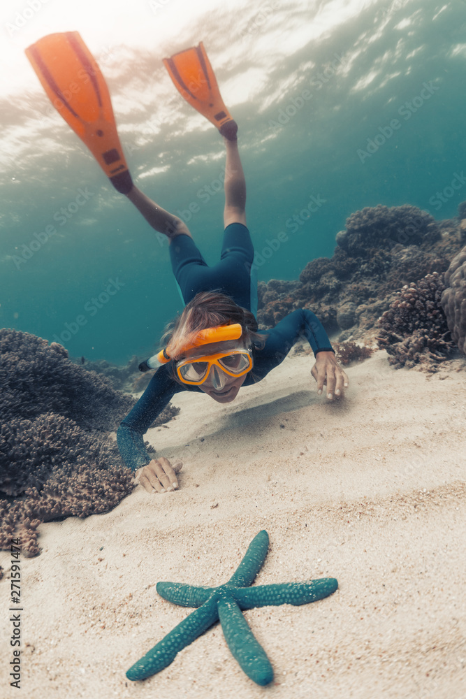 Woman snorkeling and skin diving in the tropical sea and gets closer to ...