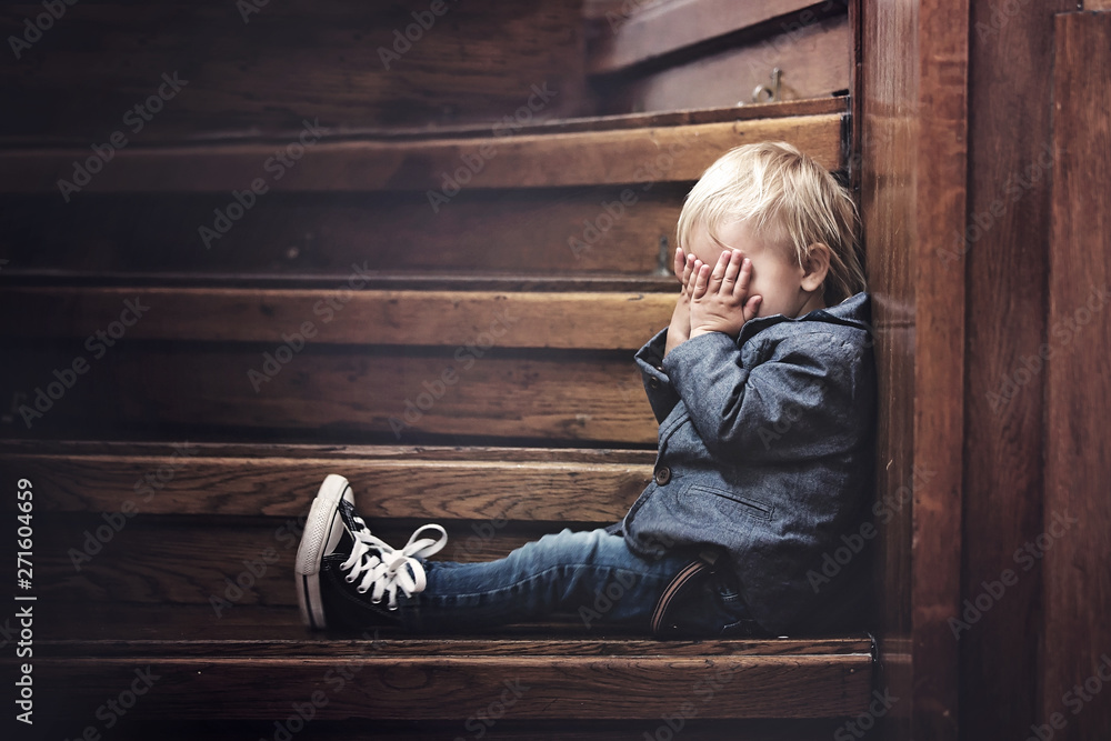 Sad child, sitting on a staircase in a big house, concept for bullying ...