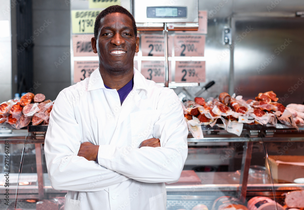 Confident male owner of butcher shop standing with arms crossed in ...