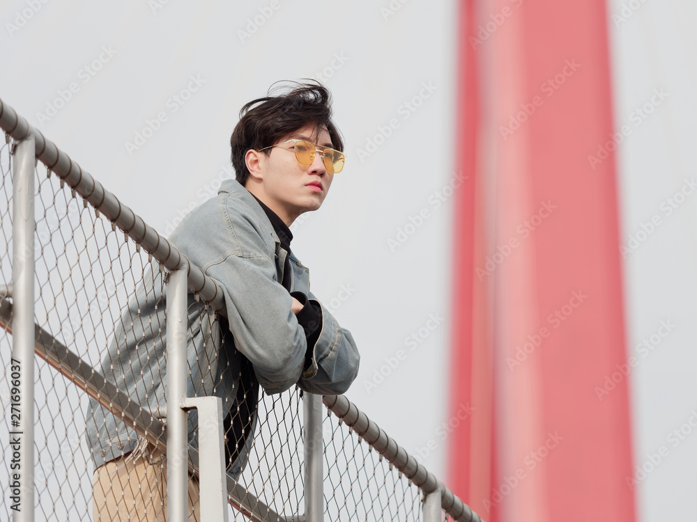 Portrait of a handsome Chinese young man standing on bridge and looking ...