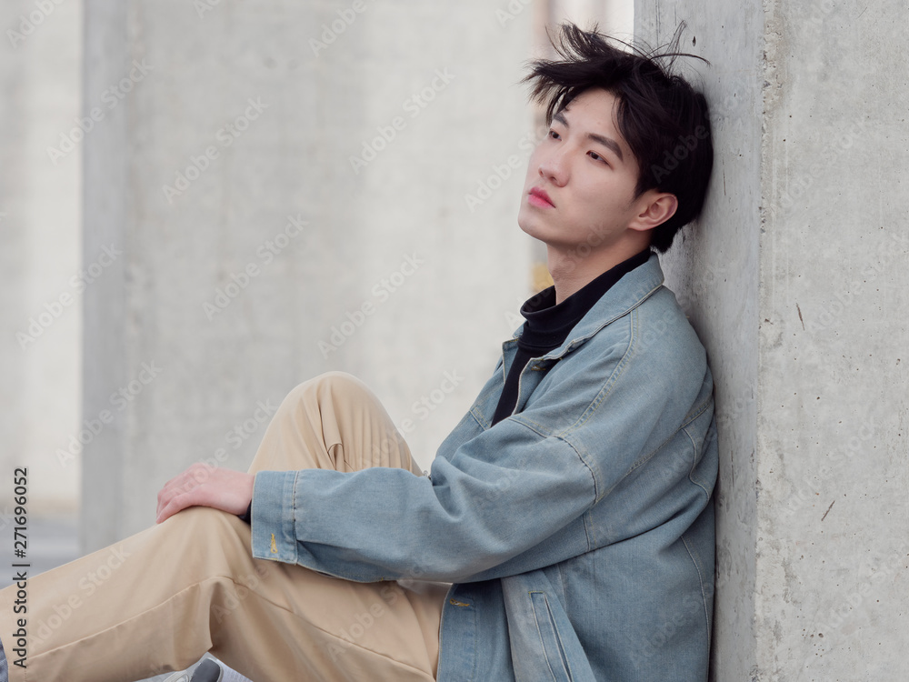Portrait of a handsome Chinese young man sitting and looking away with ...
