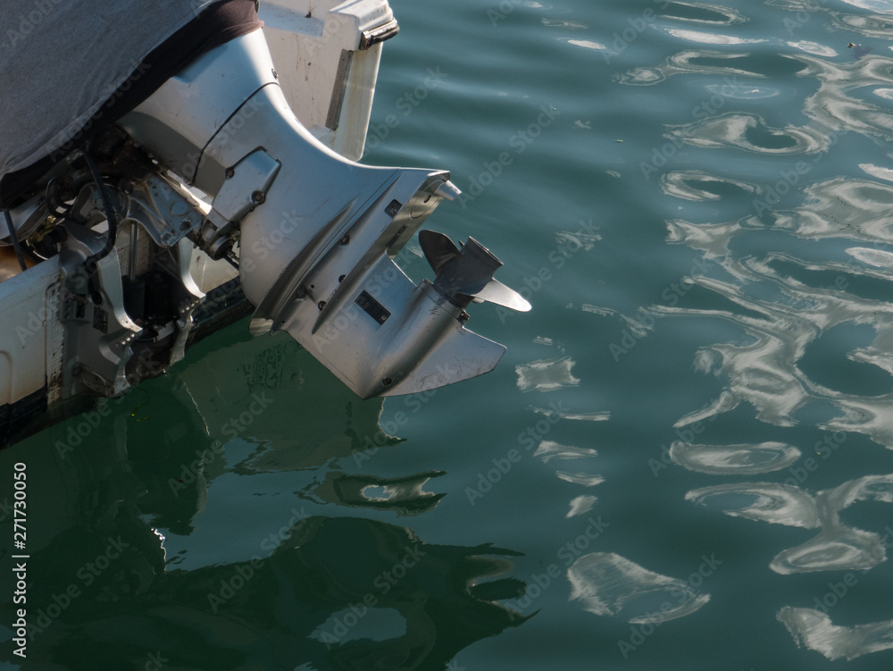 Outboard motor with propellor out of water, on the back of a small boat ...