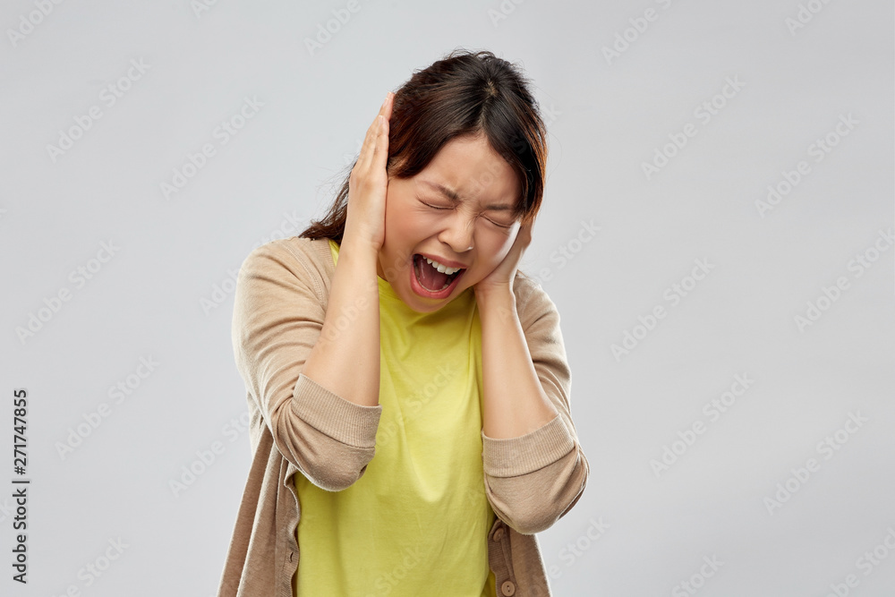 people, emotion and stress concept - asian young woman closing ears by ...