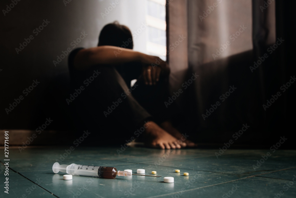 Conceptual image on the subject of drug addiction.man sitting and hugs ...