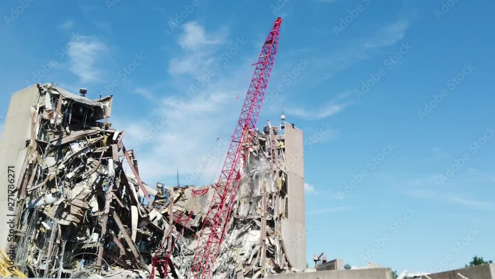 Tall red crane is seen raising it's concrete wrecking ball and then ...