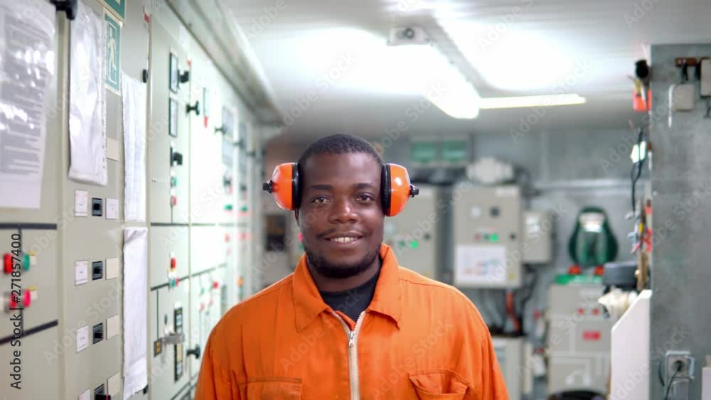 African marine engineer officer in engine control room ECR. He speaks ...