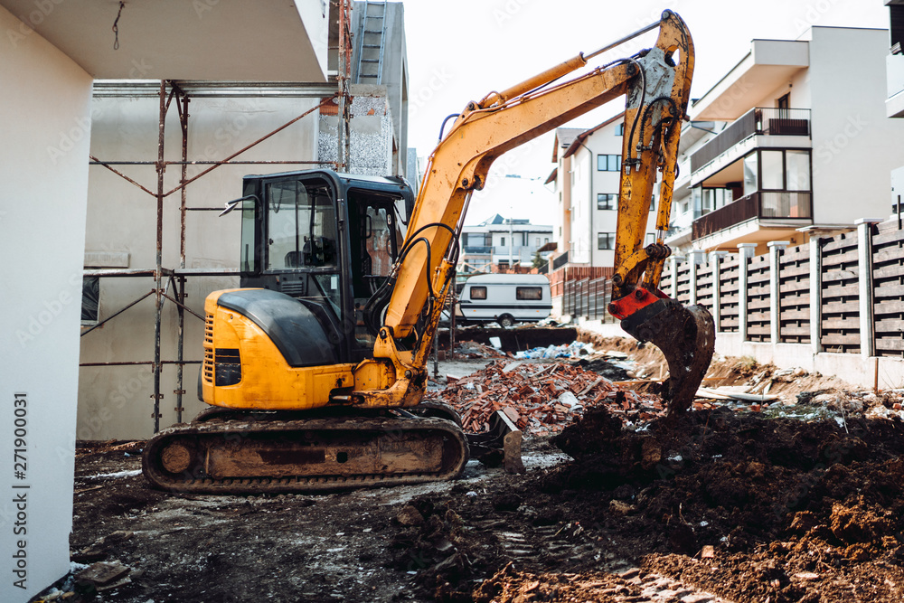 Yellow mini excavator digging foundation between construction site ...