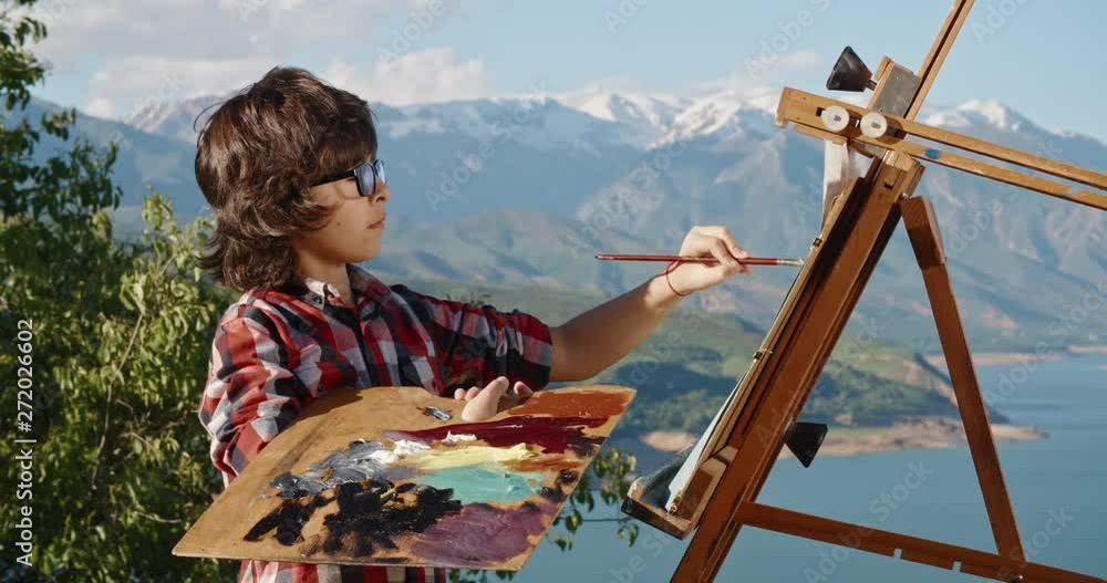 Young kid standing in front of easel, learning how to draw, creating a ...