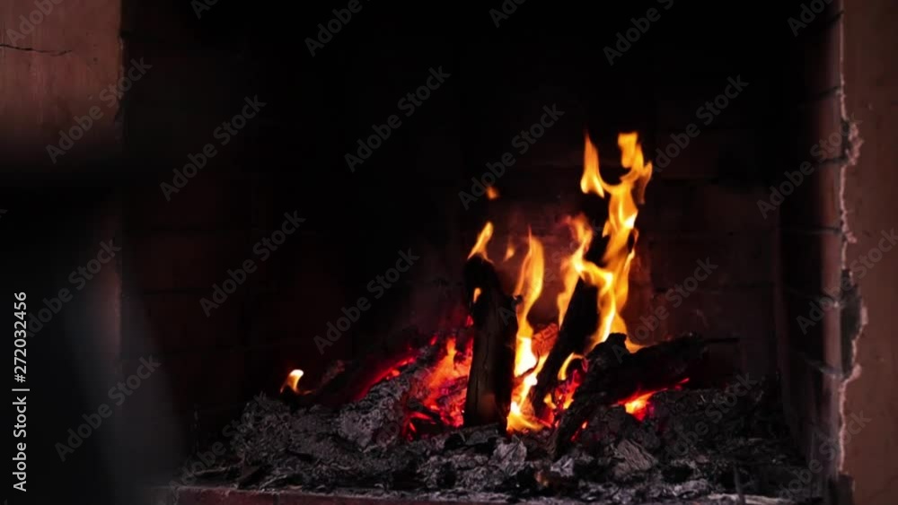 slow motion of wood on fire in a vintage fireplace with a blurry metal ...