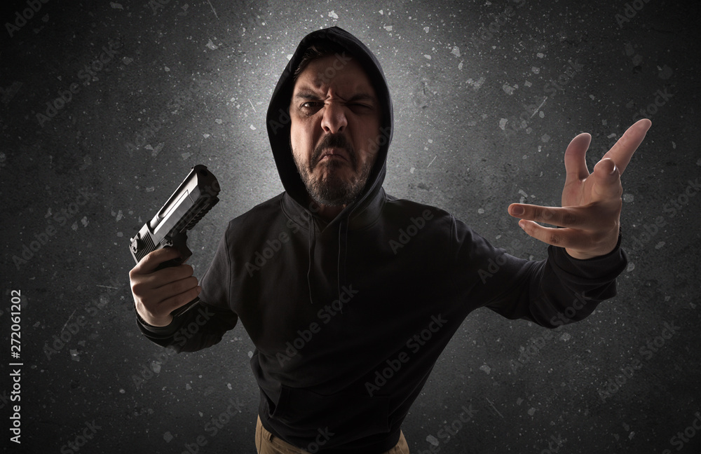 Masked armed villain in empty dark room with gun ax chainsaw mallet ...