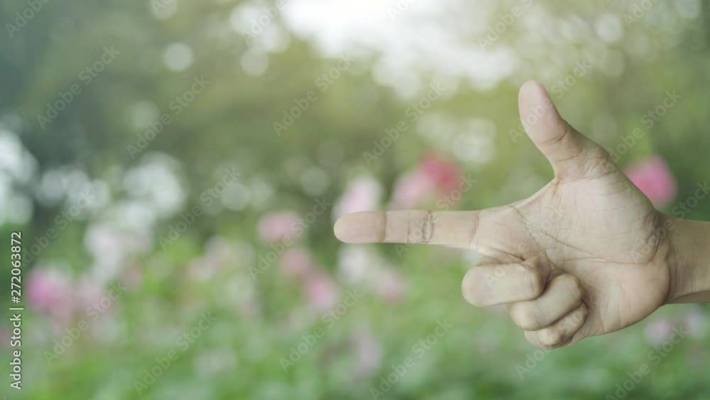 Map pin point location button on finger over blur pink flower and tree ...