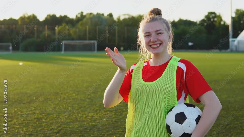 Portrait of smiling teenage girl football player with soccer ball ...