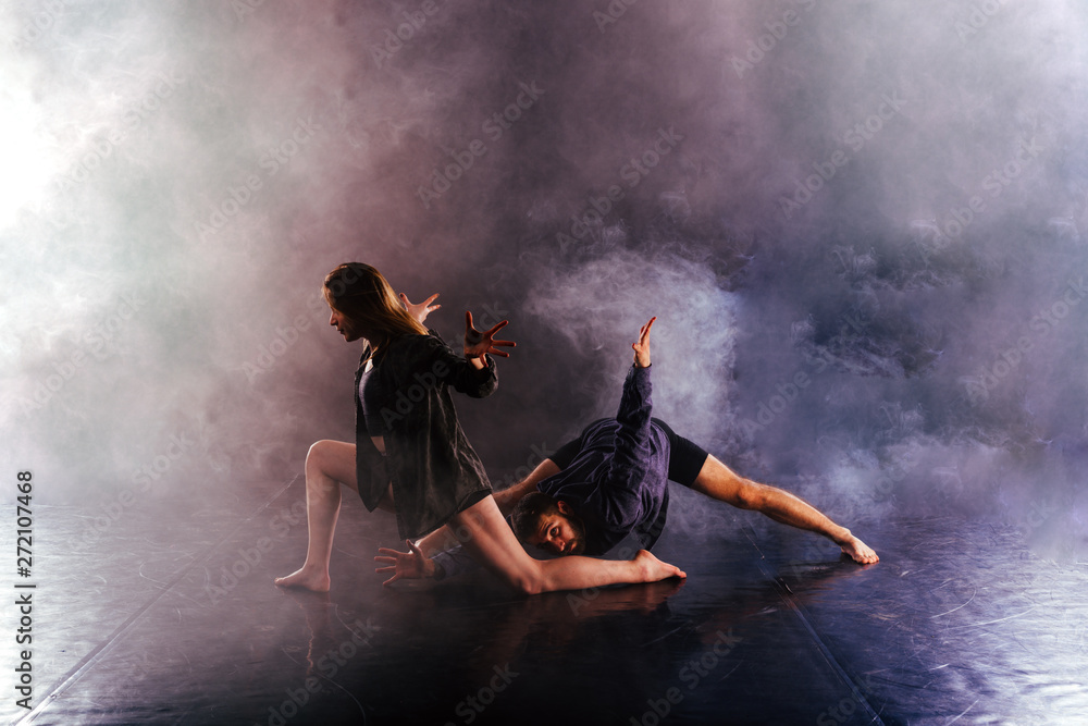 Modern dance couple twisting their legs and lening close to the ground ...