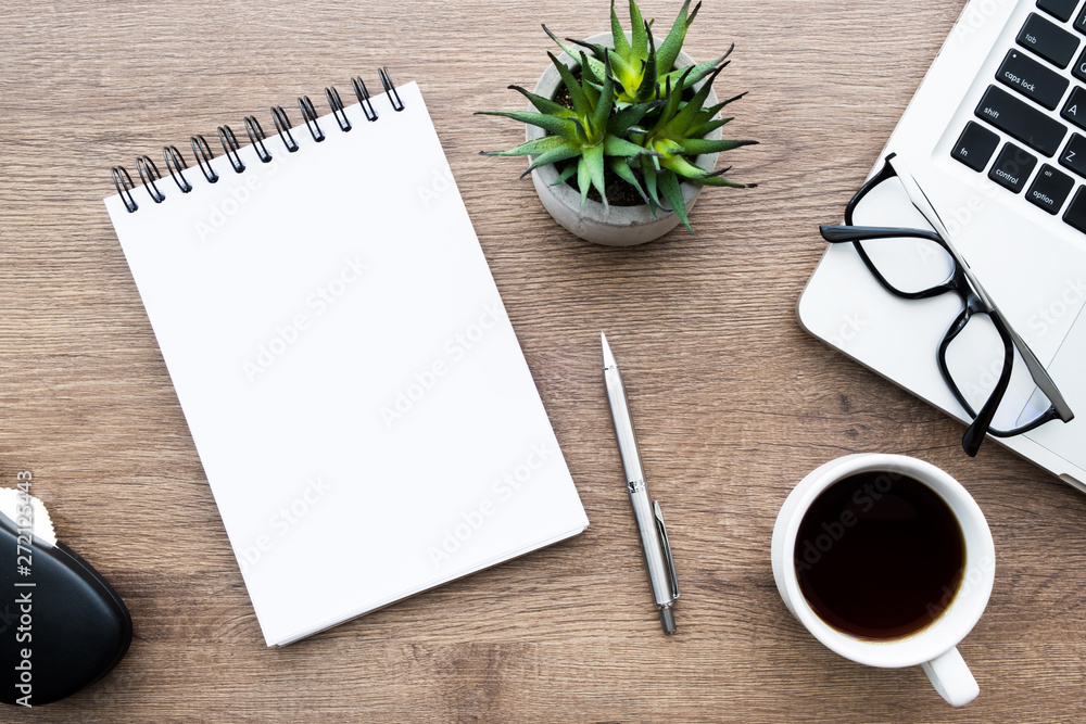 Blank notepad is on top of wood office desk table with laptop computer ...