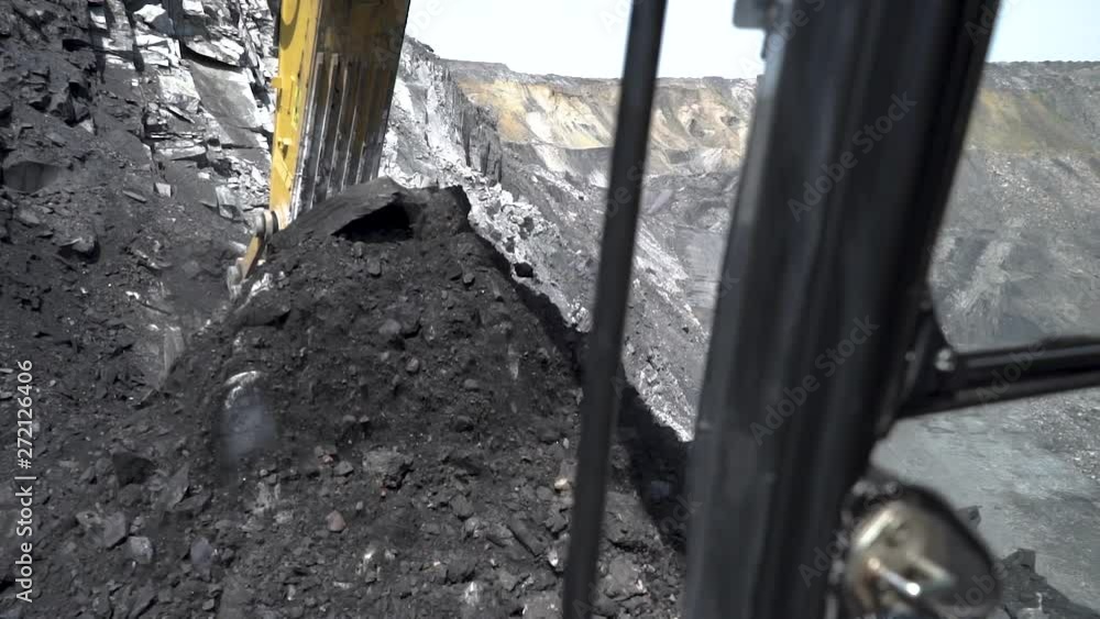 Close-up of a bucket digging coal and dumping it in the back of a dump ...