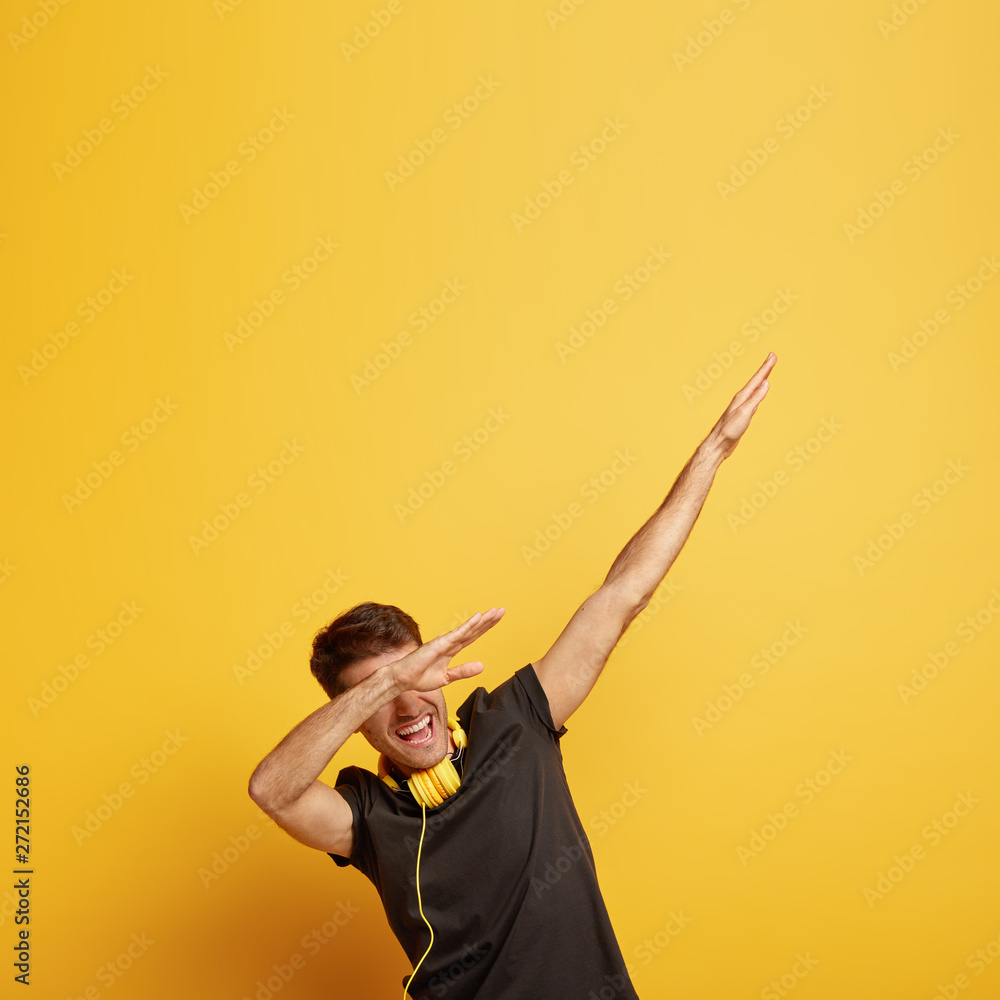 Cheerful young man makes dab dance gesture, shows dabbing movement, has ...