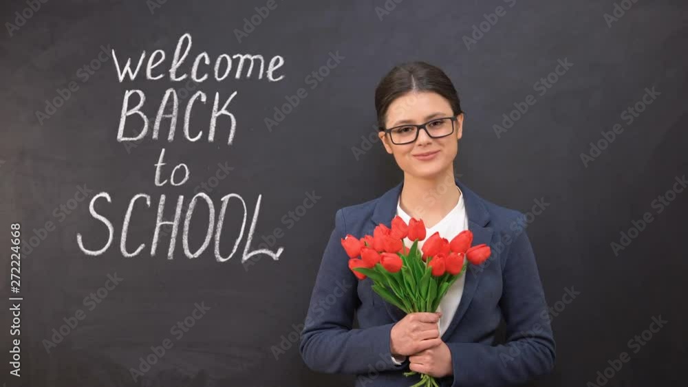 Lady teacher smiling and holding bunch of tulips, welcome back to ...