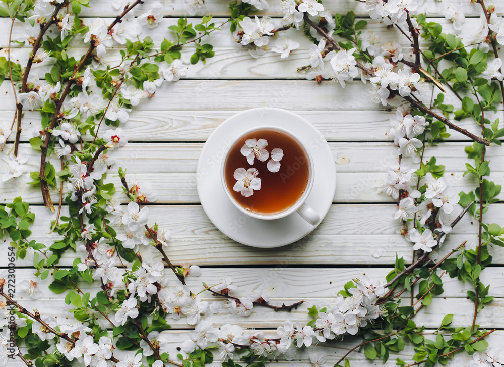 White cup and apricot tea dish with branches of flowering apricot. The ...