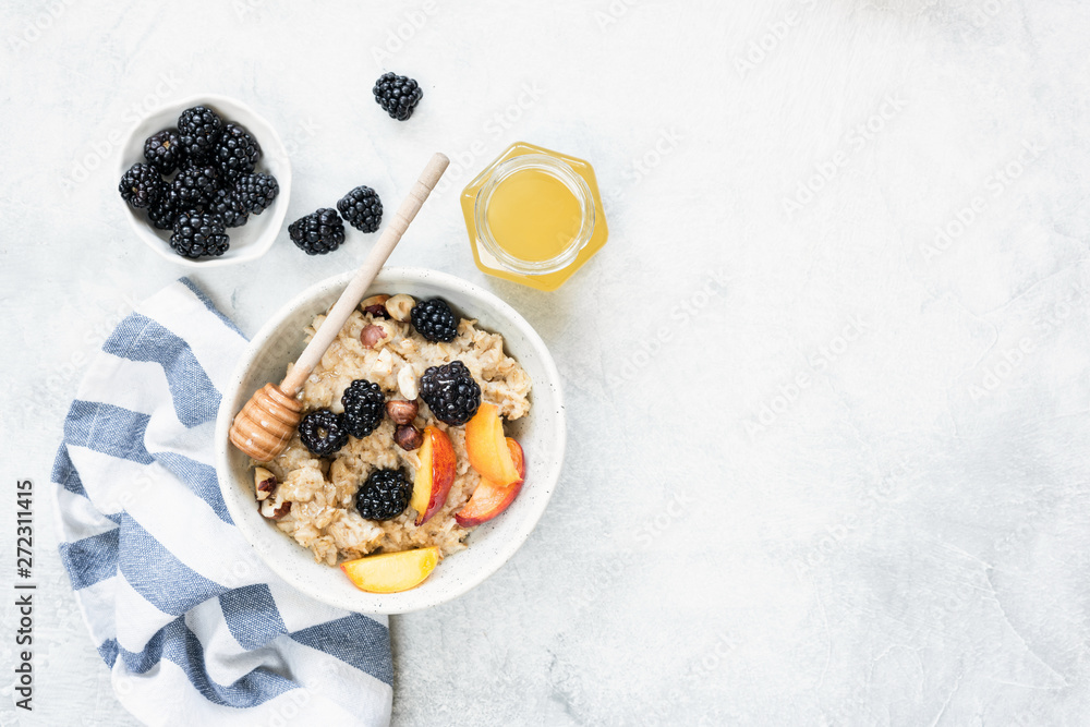 Oatmeal porridge bowl with fruits and honey on grey concrete background ...