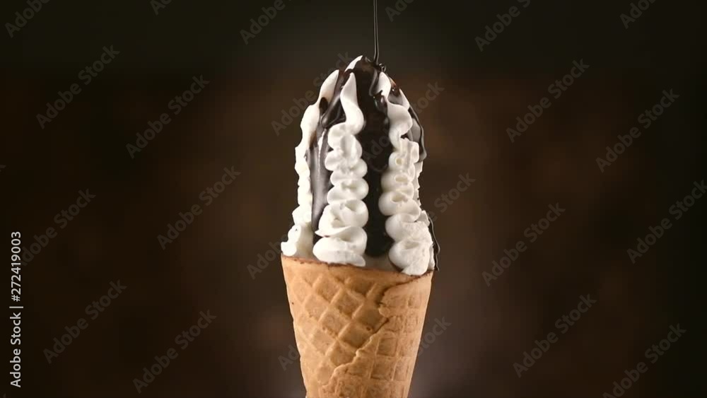 Ice cream cone close-up. Pouring chocolate syrup topping on Icecream in ...