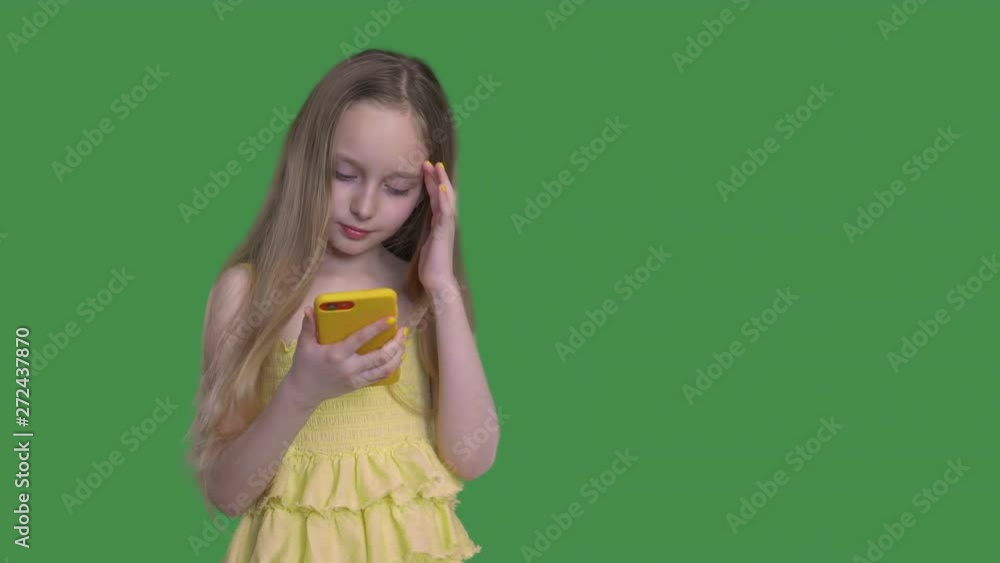 Teen cute girl in yellow dress with windy long hairs is browsing her ...