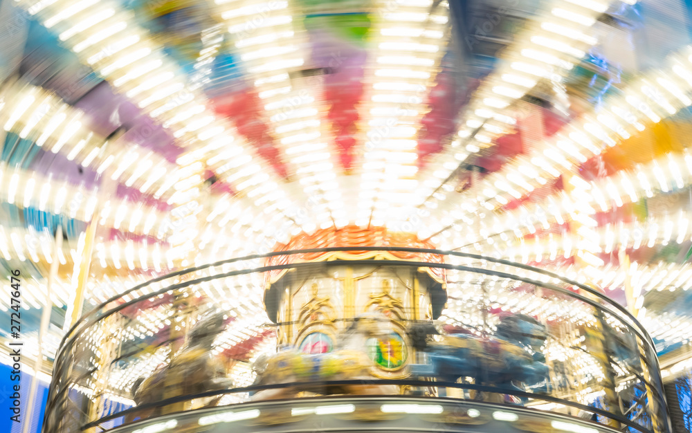 moving and unfocused effect of a merry-go-round with colorful lights at ...